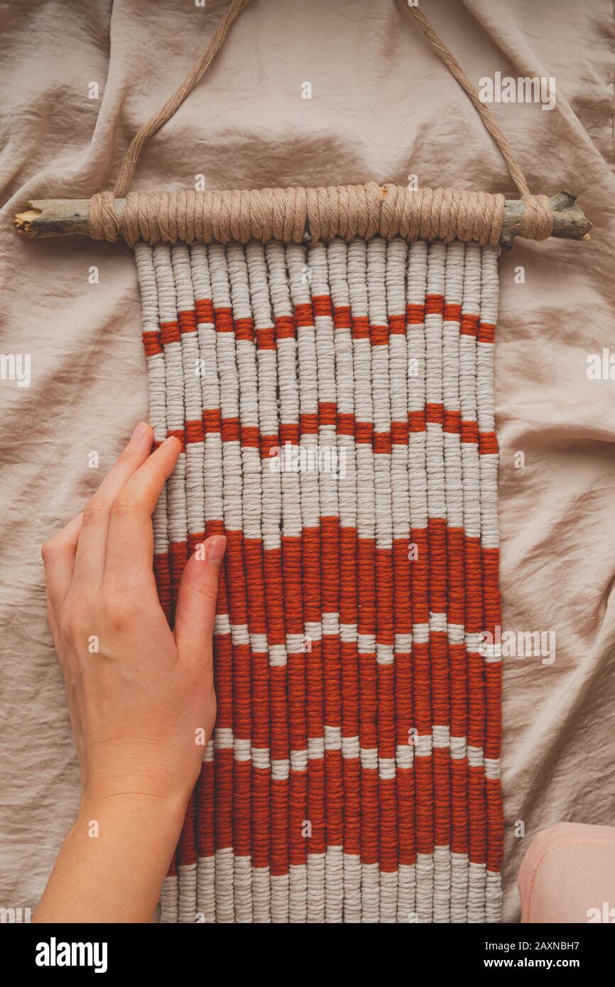 Handcrafted macrame wall hanging, close-up view. Human hand touches a ...