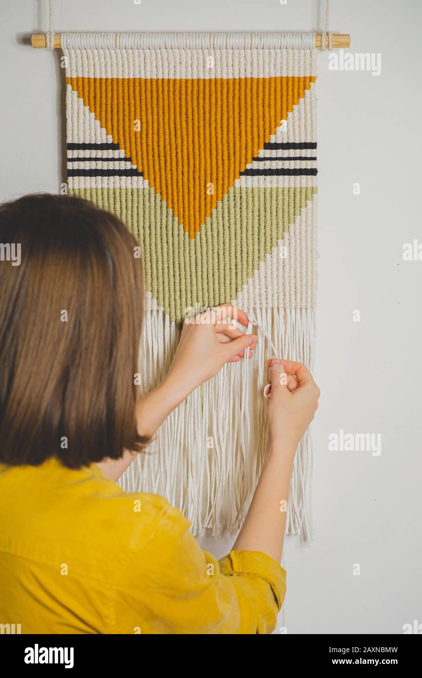 Woman doing macrame craft. Hand-making a cotton rope wall-hanging decor ...