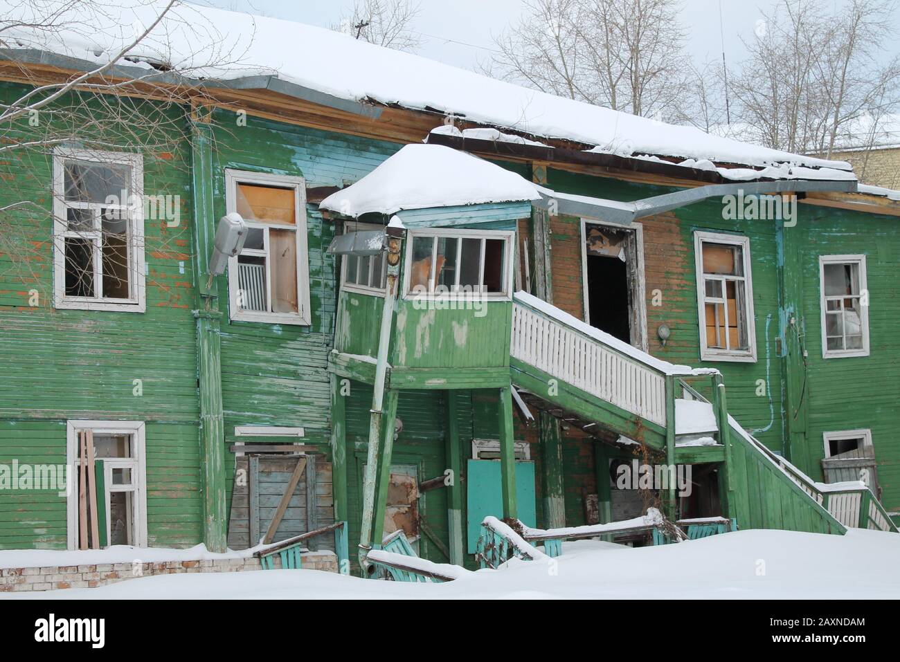 Ruined old two-story apartment building. Green wooden house with stairs ...
