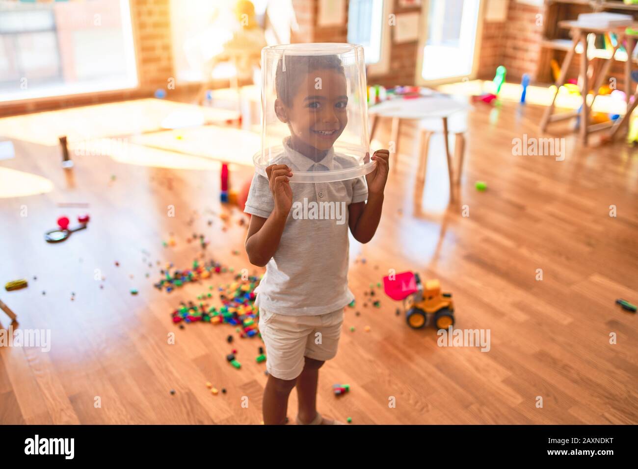 Beautiful african american toddler playing with plastic cube on head as ...