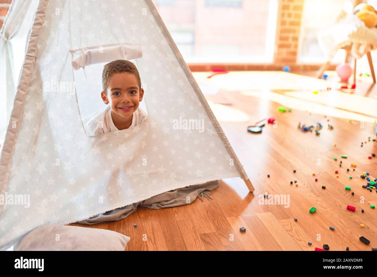 Beautiful african american toddler playing inside tipi smiling at ...