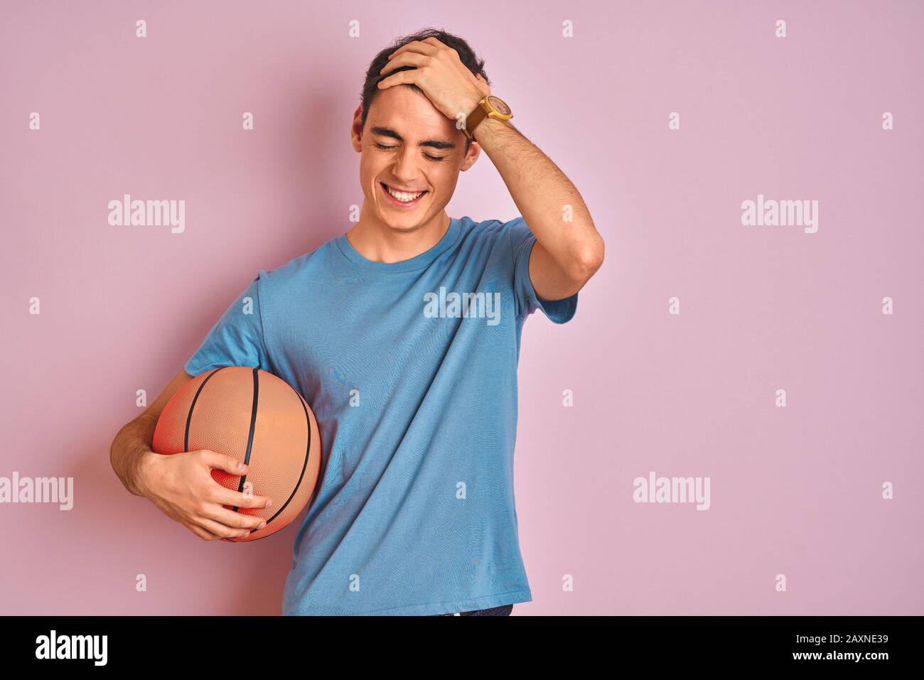 Teenager boy holding professional basket ball over isolated pink ...