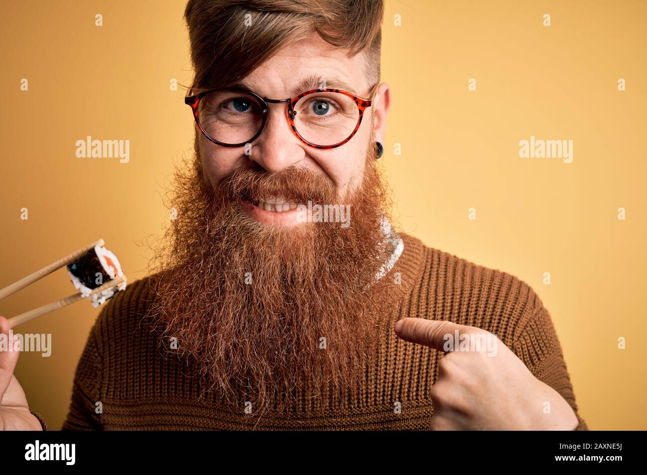 Redhead Irish man with beard eating salmon maki sushi using chopsticks ...