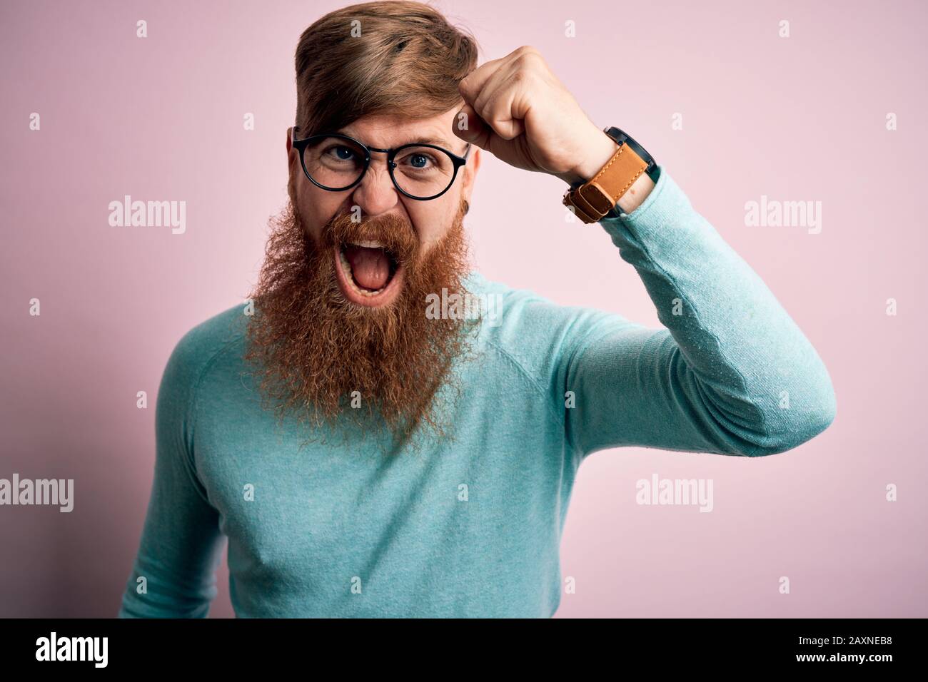Handsome Irish redhead man with beard wearing glasses over pink ...