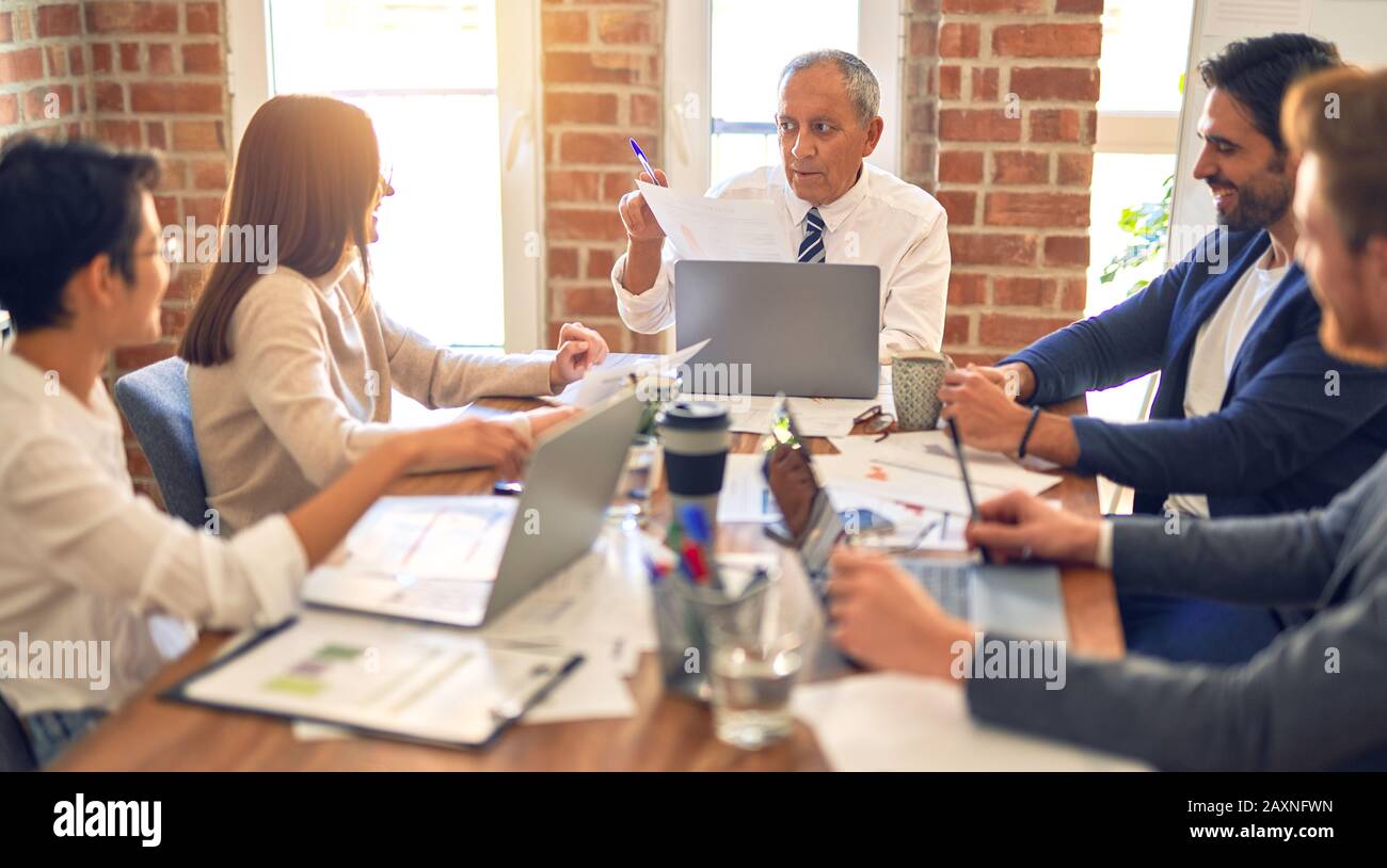 Group of business workers working together. Sitting on desk using ...