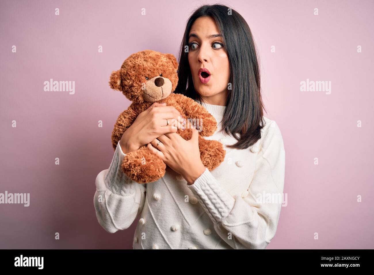 Young brunette woman with blue eyes hugging teddy bear stuffed animal ...
