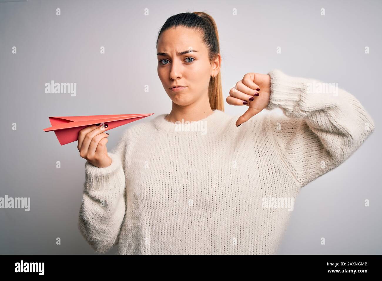 Beautiful blonde woman with blue eyes holding red paper airplane over ...