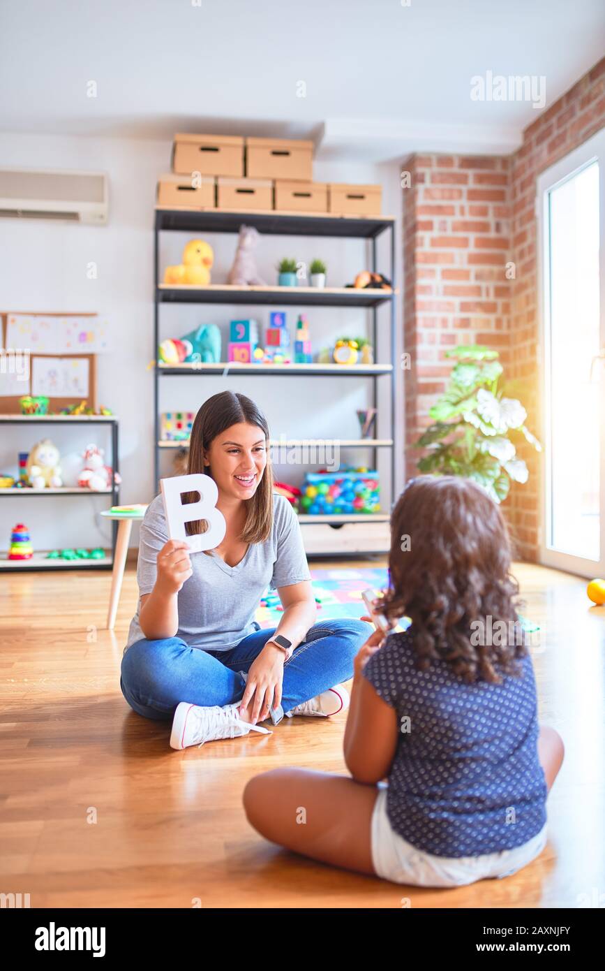 Beautiful teacher teaching alphabet to student toddler girl at ...
