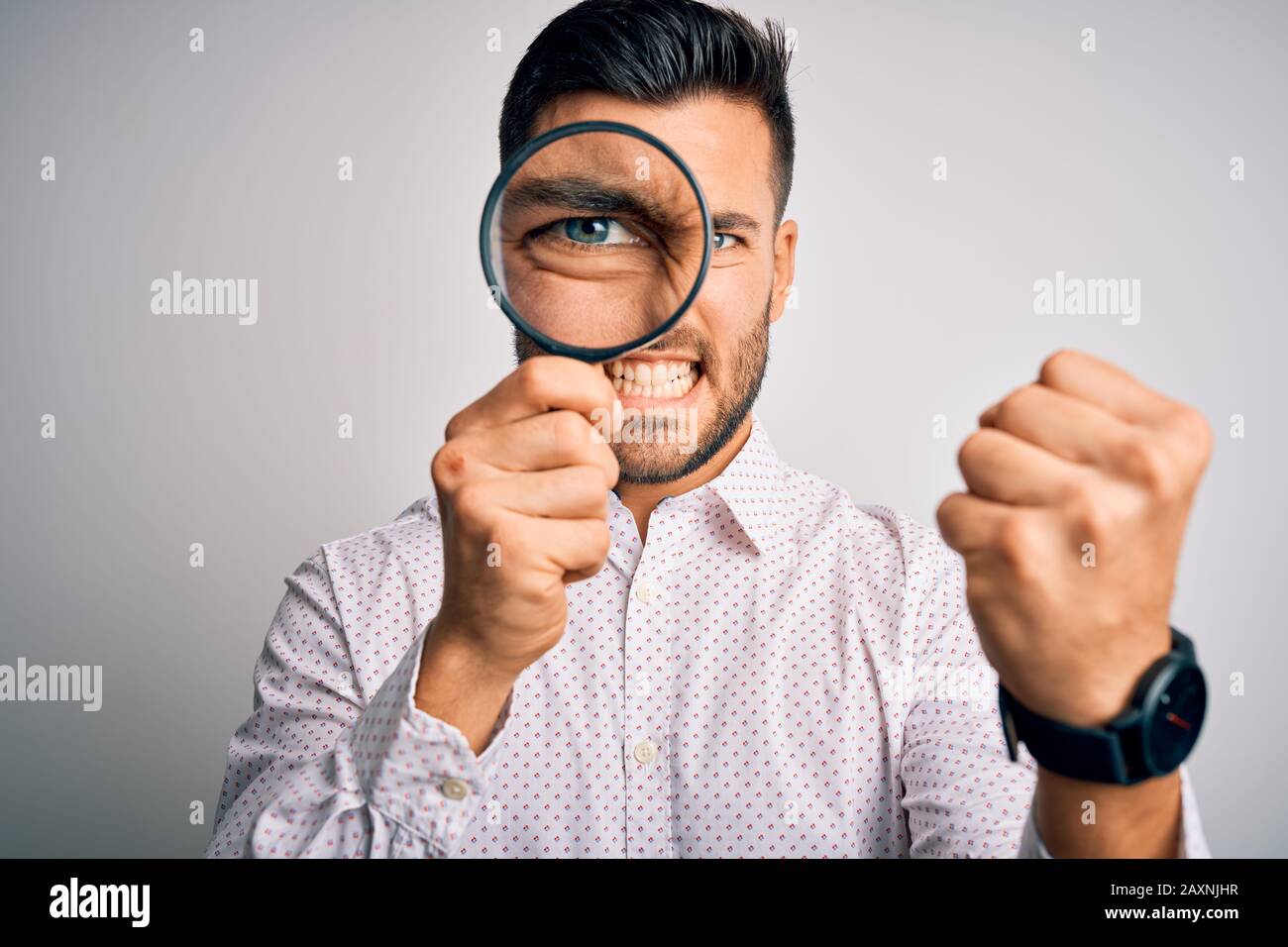 Young detective man looking through magnifying glass over isolated ...