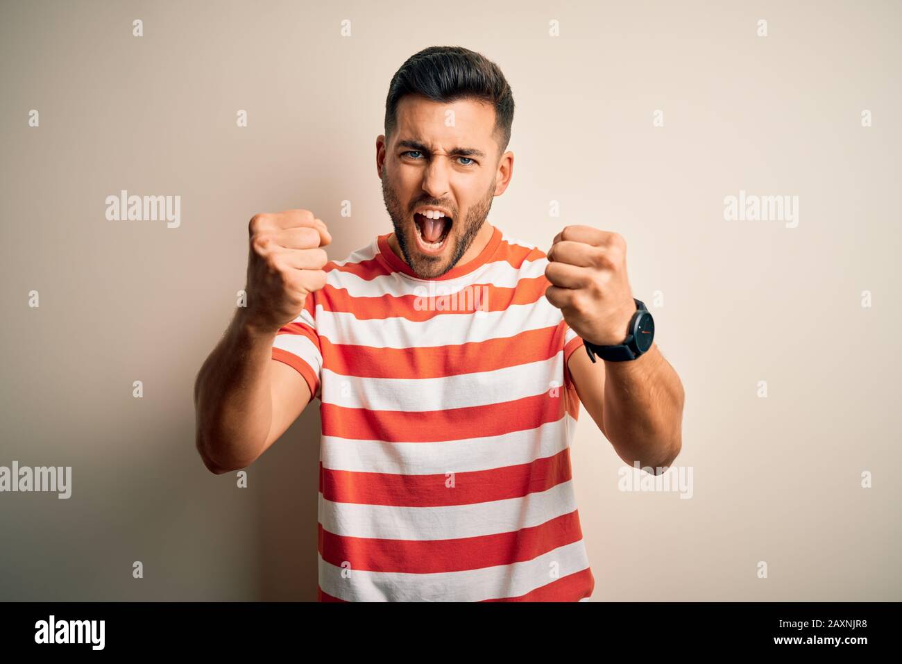 Young handsome man wearing casual striped t-shirt standing over ...