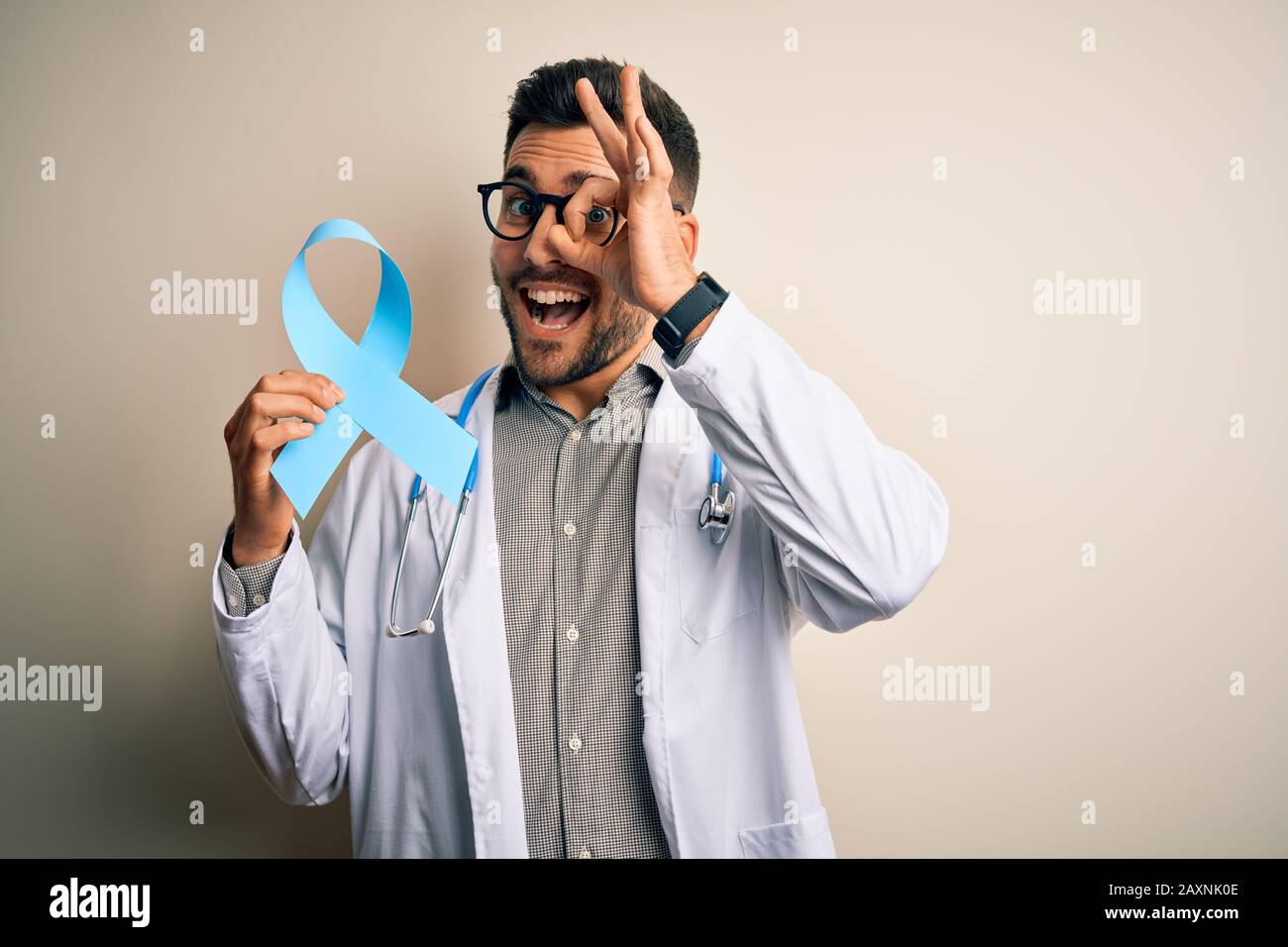 Young professional doctor man holding colon awareness blue ribbon over ...