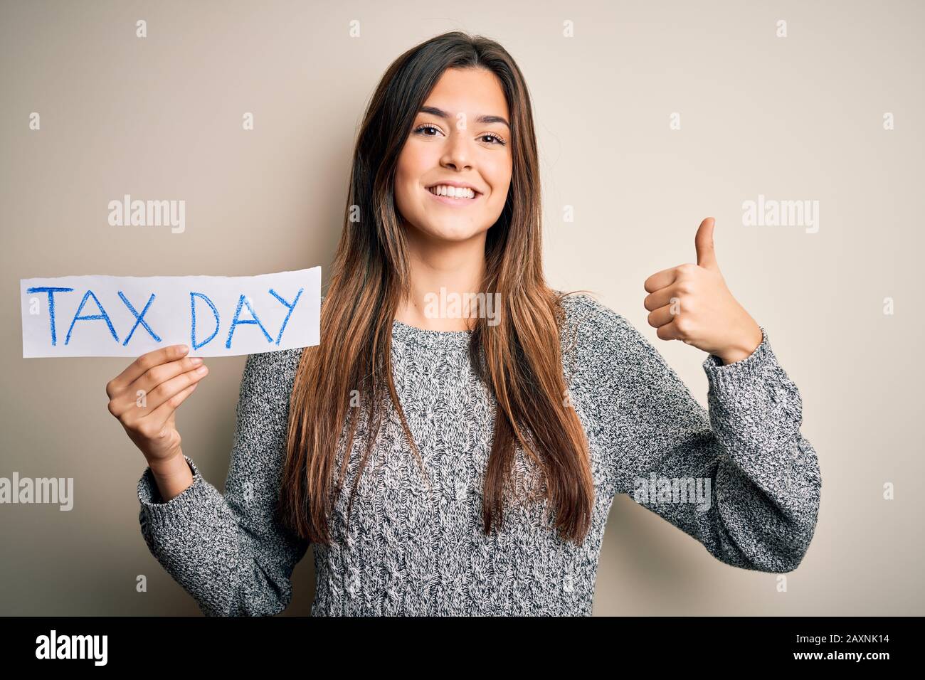 Young beautiful girl holding paper with tax day message standing over ...