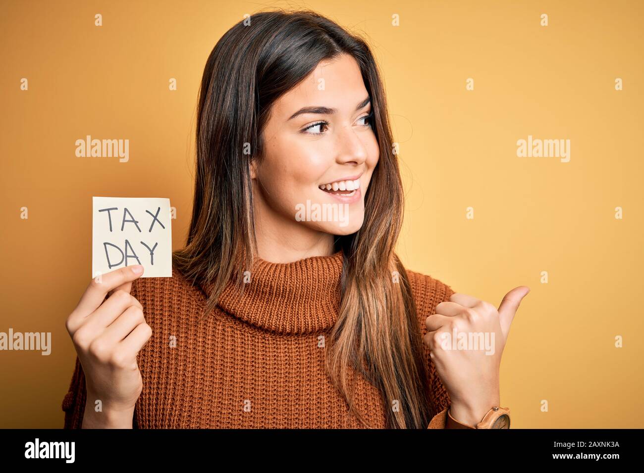 Young beautiful girl holding reminder paper with tax day message over ...