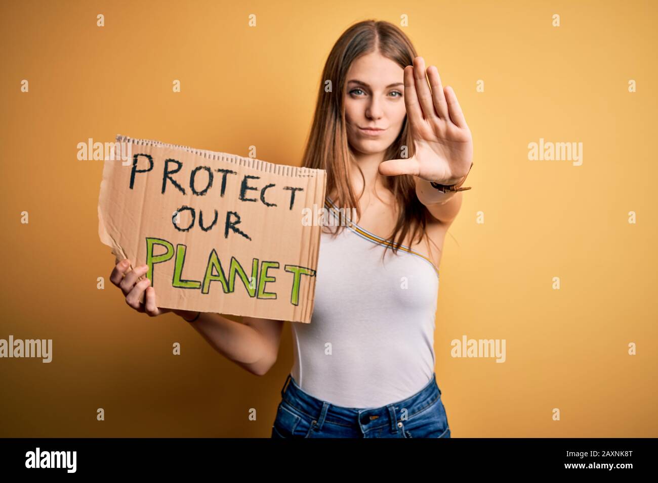 Young redhead woman asking for enviroment holding banner with protect ...