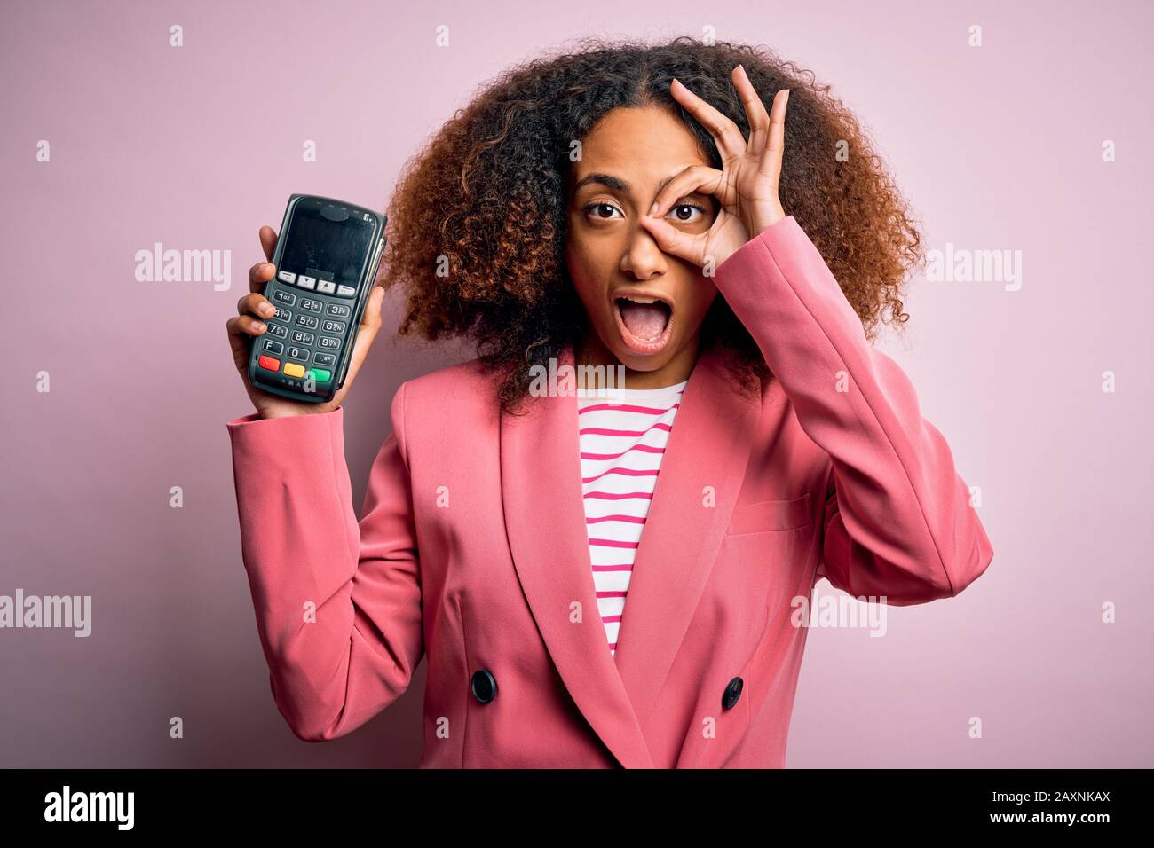 Young african american woman with afro hair holding dataphone over pink ...