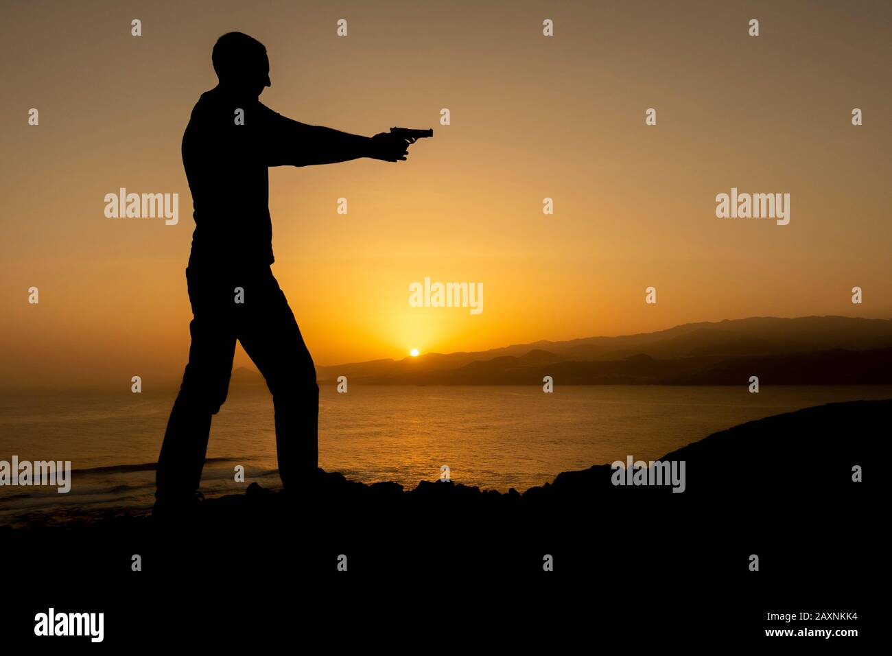 Silhouette of man holding gun at sunset near ocean Stock Photo - Alamy
