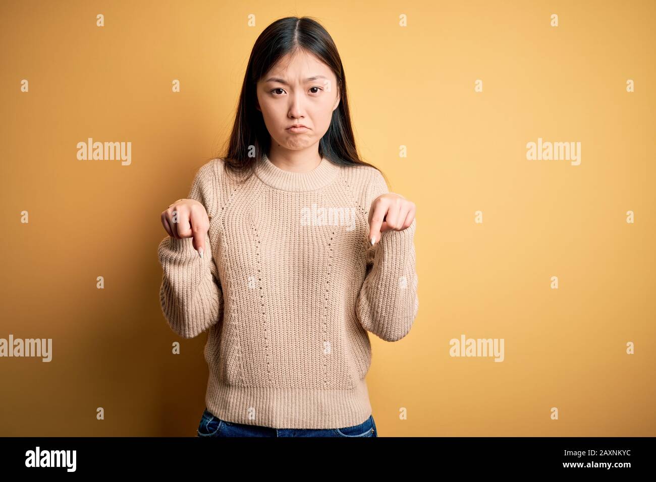 Young beautiful asian woman wearing casual sweater over yellow isolated ...