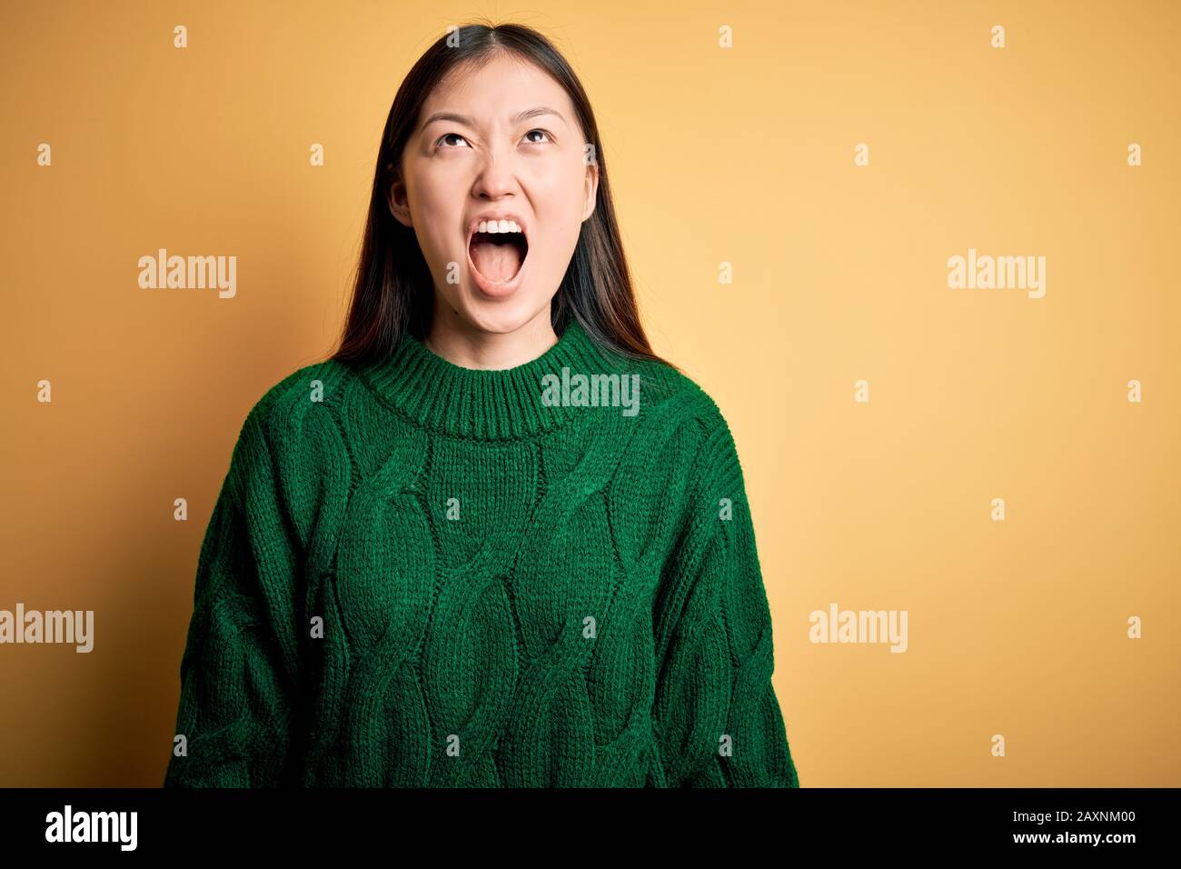 Young beautiful asian woman wearing green winter sweater over yellow ...
