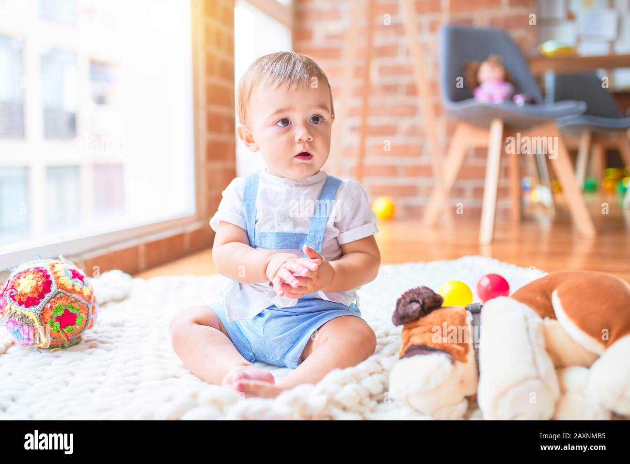 Beautiful toddler sitting on the blanket around lots of toys at ...