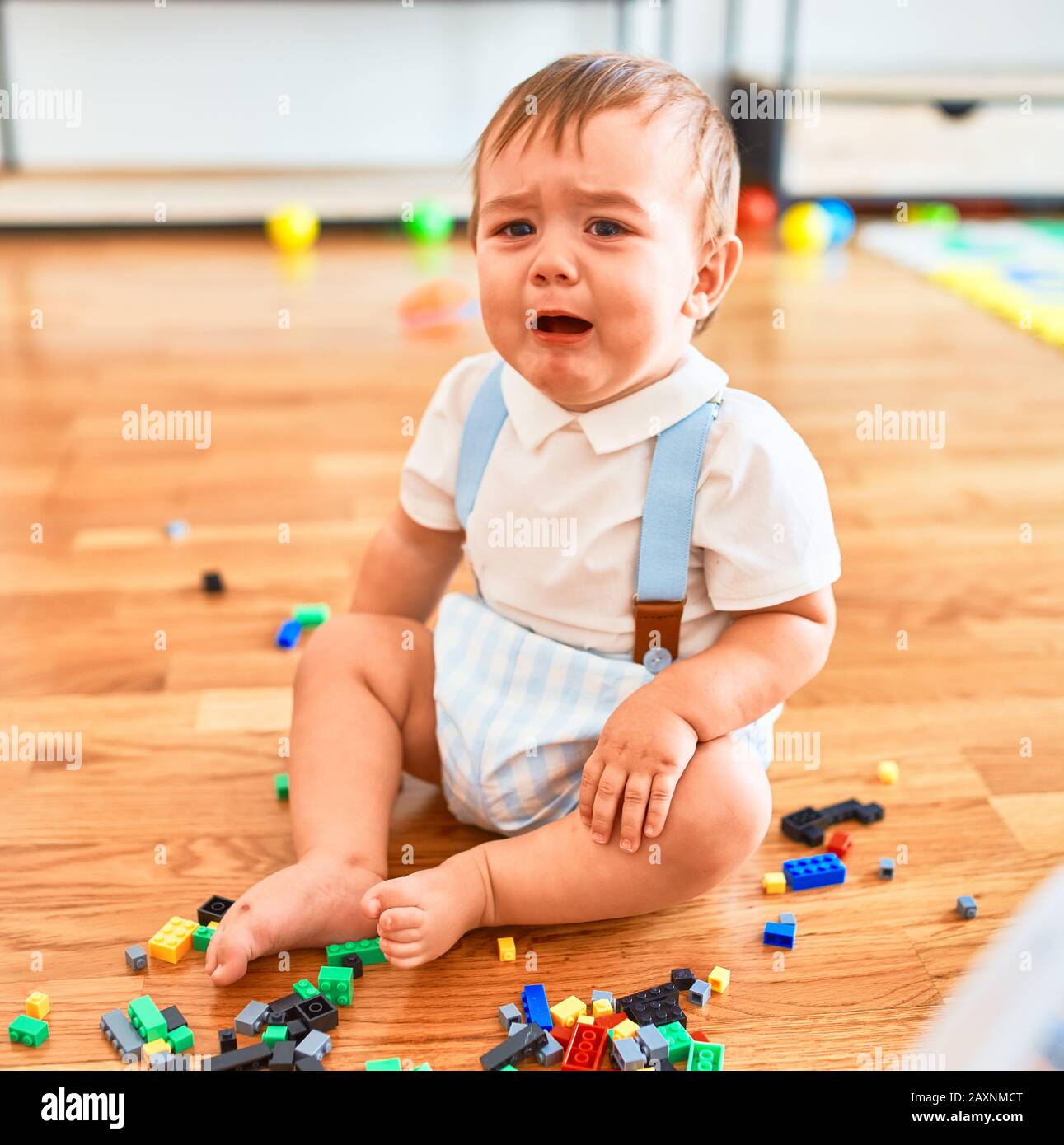 Adorable toddler crying around lots of toys at kindergarten Stock Photo ...