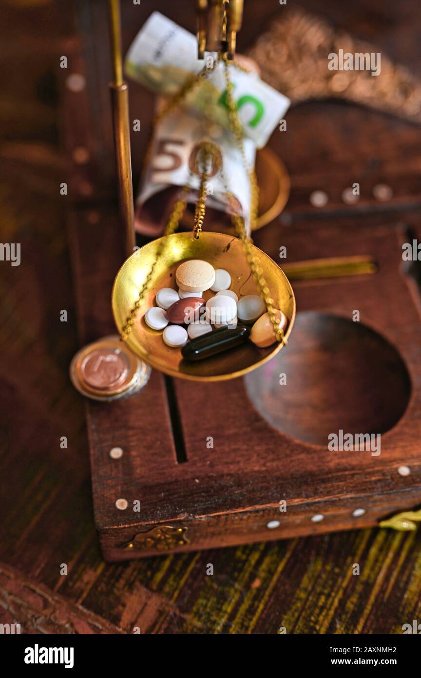 An old scale with money on one side and tablets on the other as a ...
