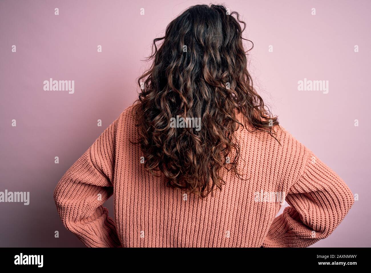 Young beautiful woman with curly hair wearing casual sweater over ...