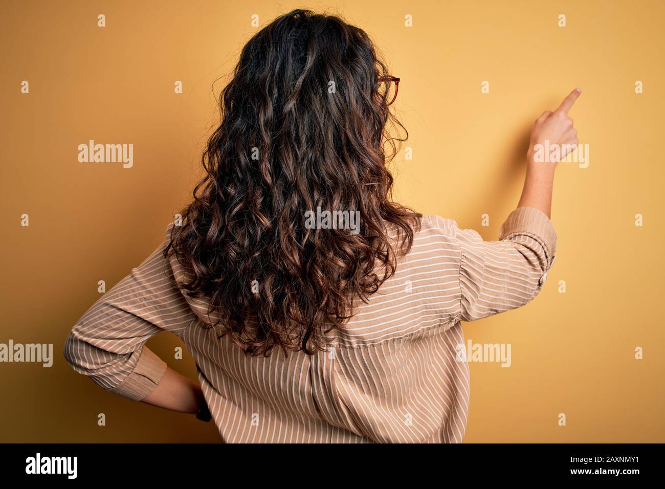 Beautiful woman with curly hair wearing striped shirt and glasses over ...