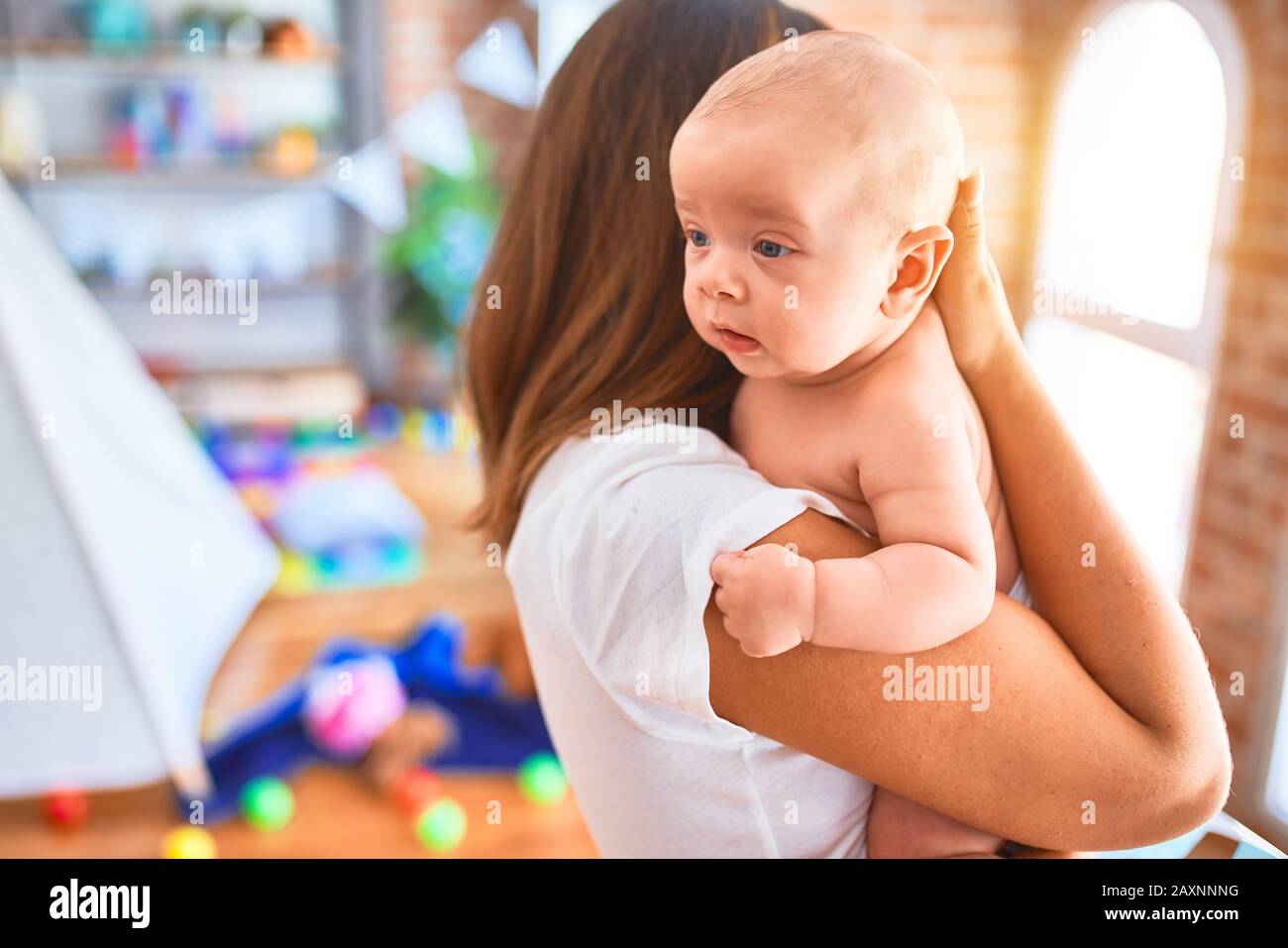 Young beautifull woman and her baby standing at home. Mother holding ...