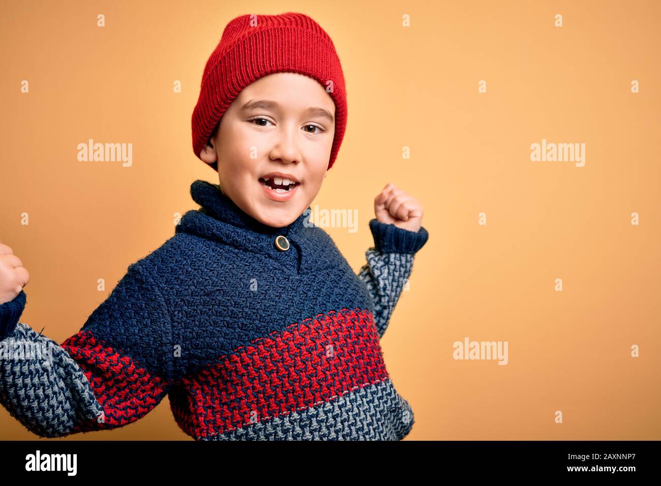 Young little boy kid wearing wool cap and winter sweater over yellow ...