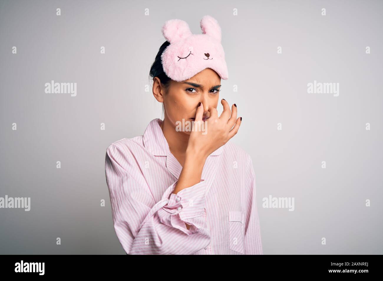 Young beautiful brunette woman wearing pajama and sleep mask over white ...