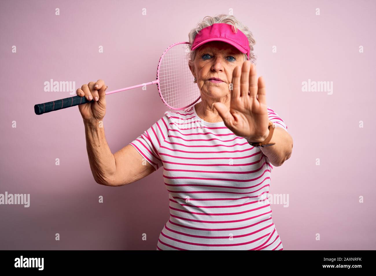 Senior beautiful sportswoman holding badminton racket over isolated ...