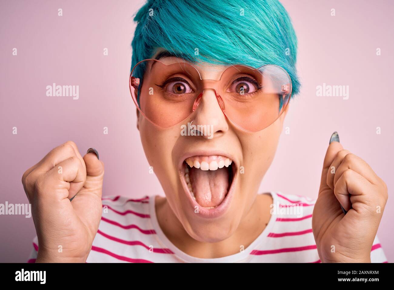 Young beautiful woman with blue fashion hair wearing fanny glasses with ...