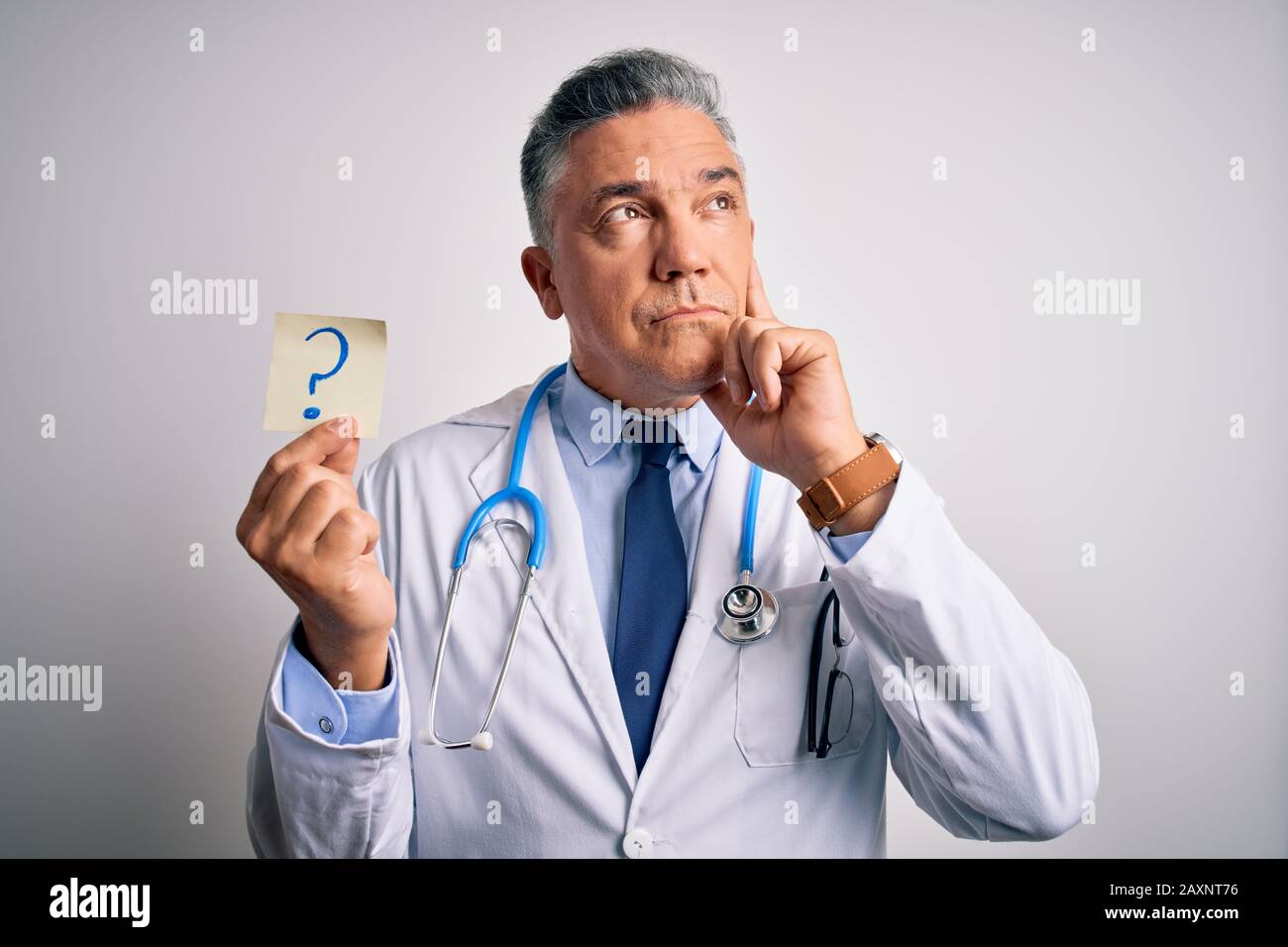 Middle age handsome grey-haired doctor man holding paper with question ...