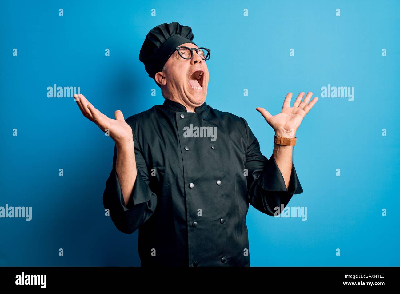 Middle age handsome grey-haired chef man wearing cooker uniform and hat ...