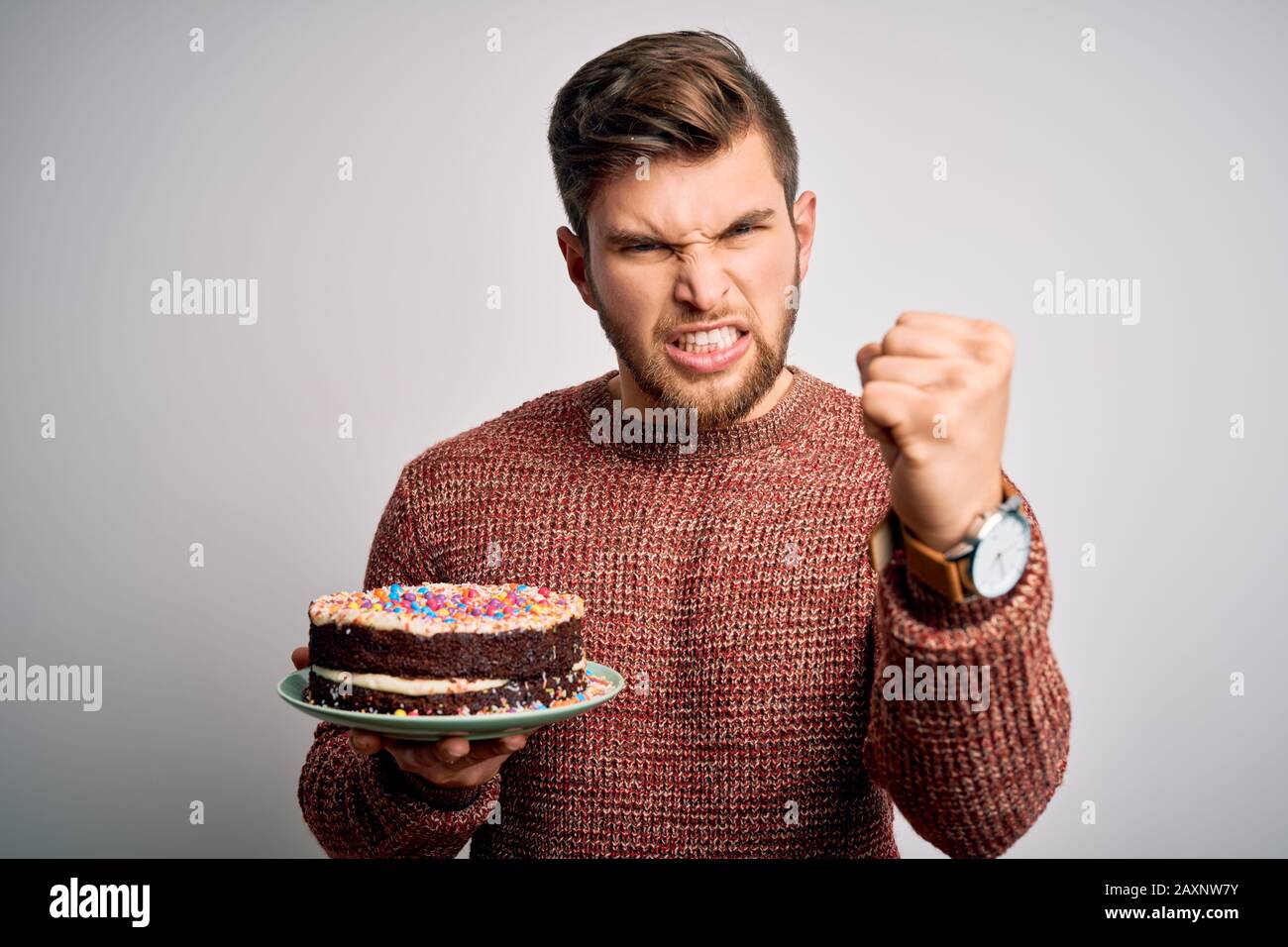 Young blond man with beard and blue eyes holding birthday cake over ...