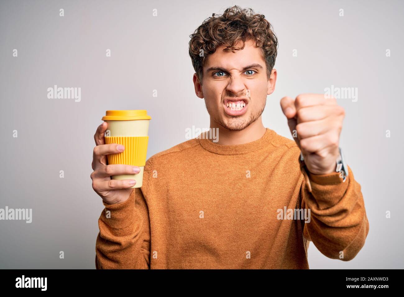 Young blond man with curly hair drinking cup of coffee standing over ...