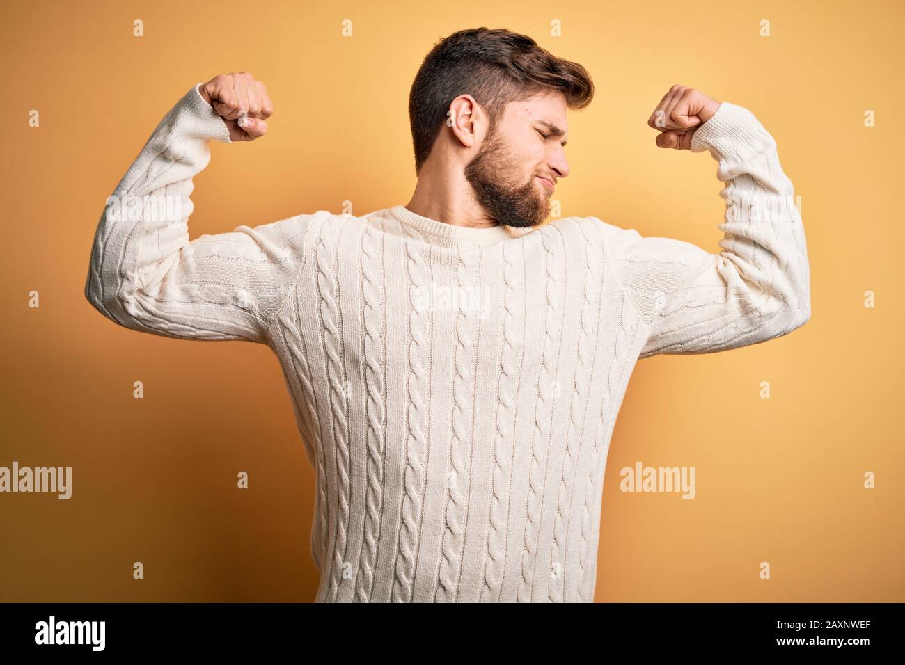 Young blond man with beard and blue eyes wearing white sweater over ...