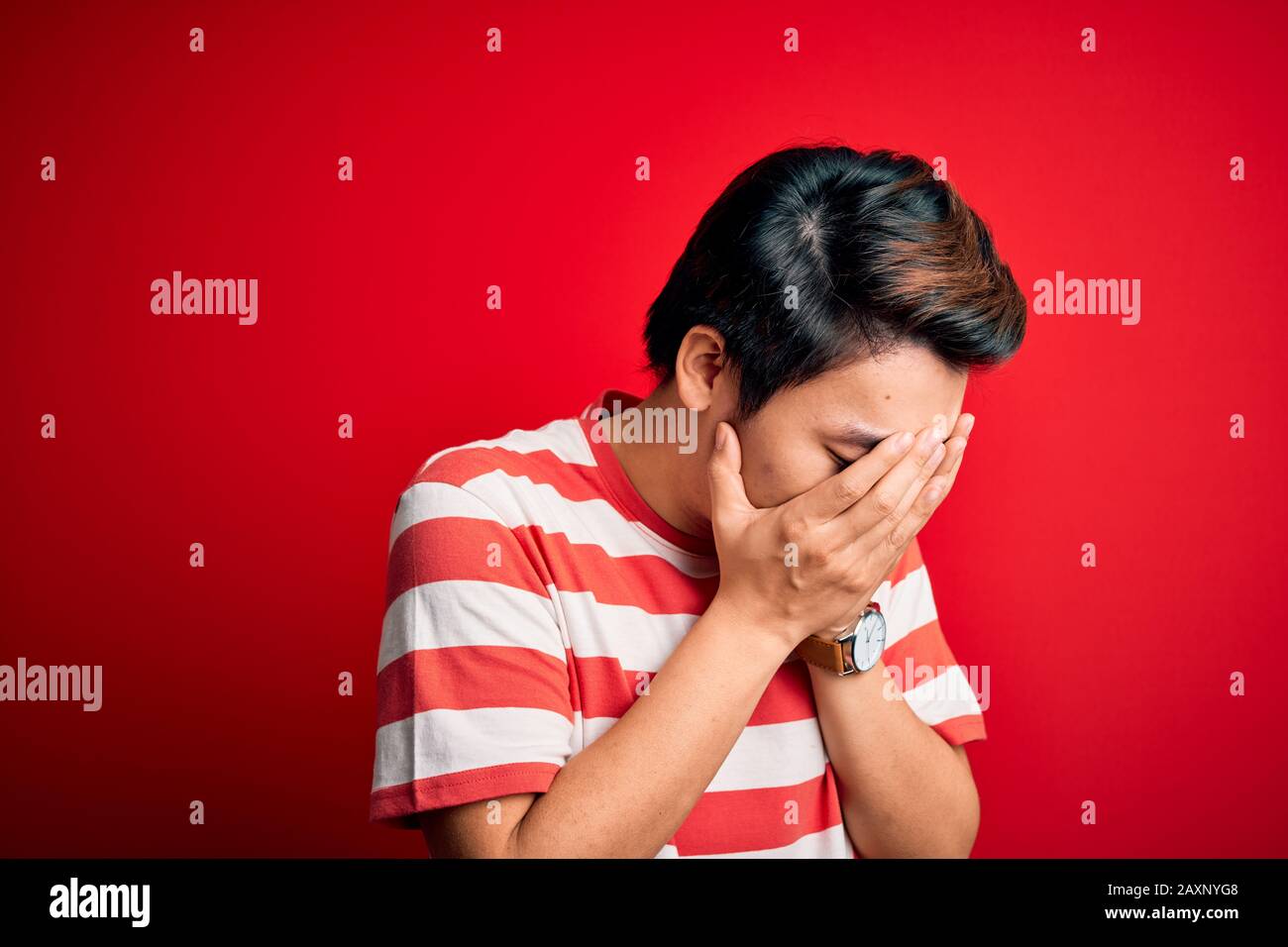 Young handsome chinese man wearing casual striped t-shirt standing over ...