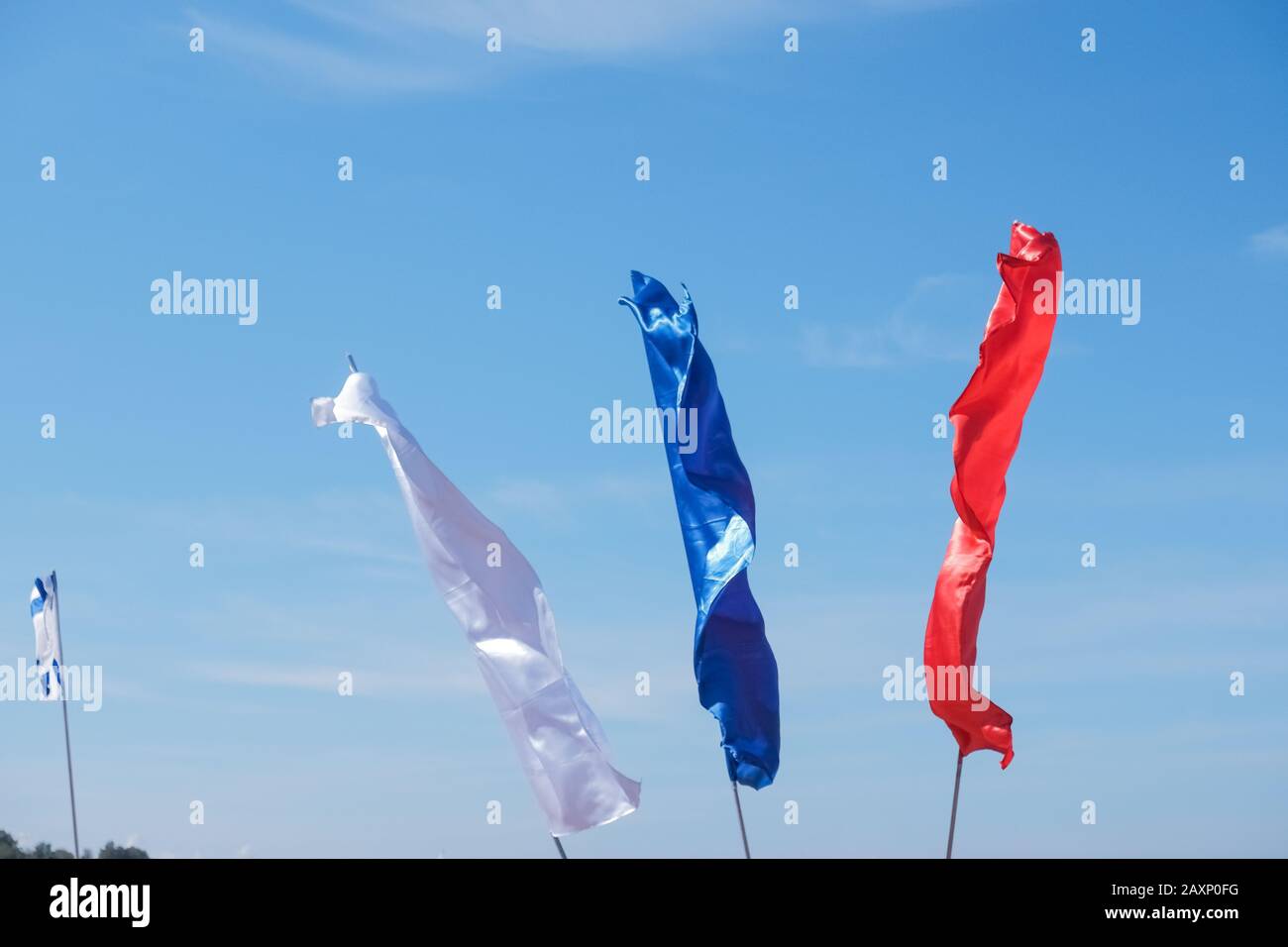 Three colorful flags on flagpoles against blue sky with perspective ...