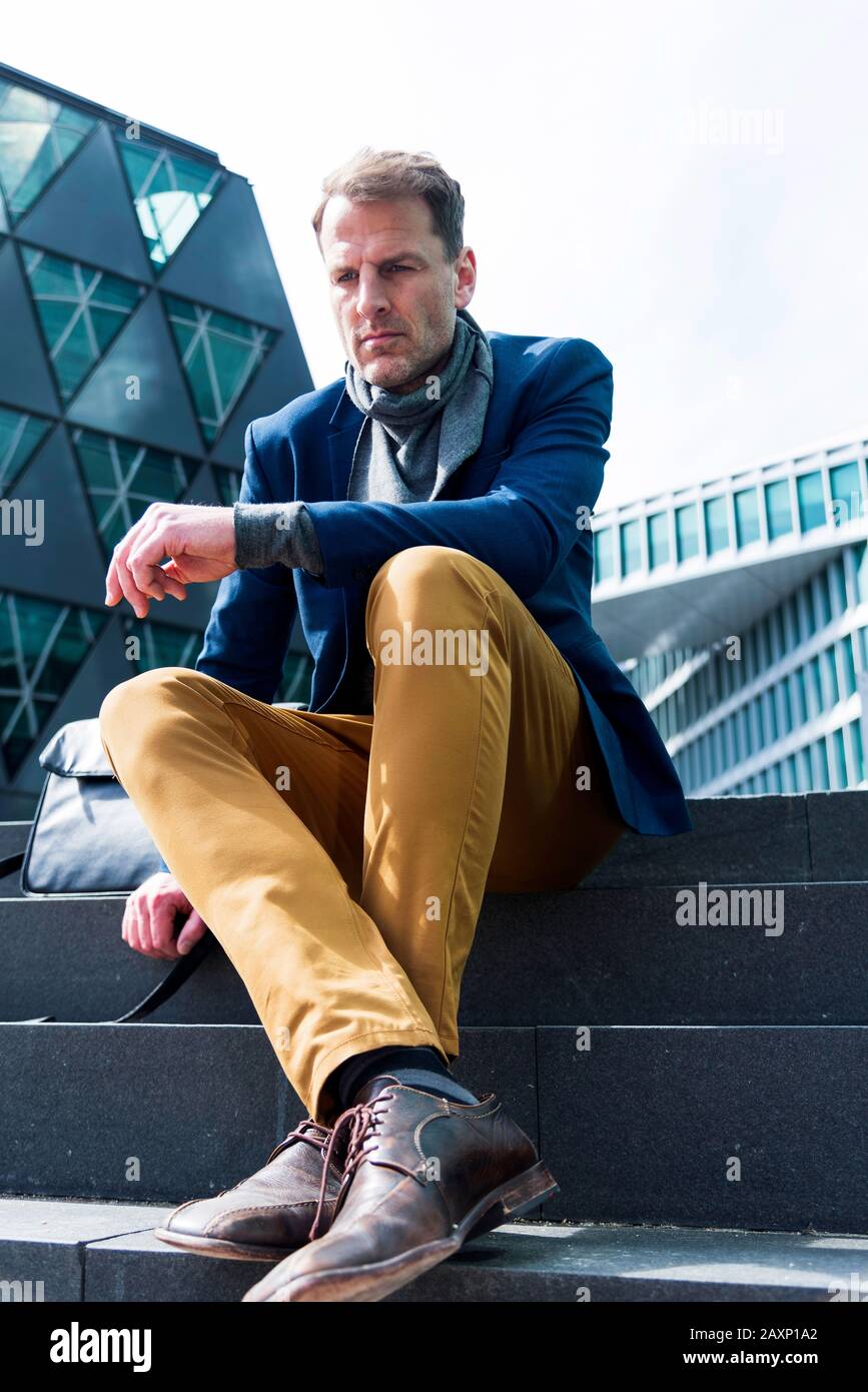 Businessman sits in front of modern office buildings, Frankfurt on the ...