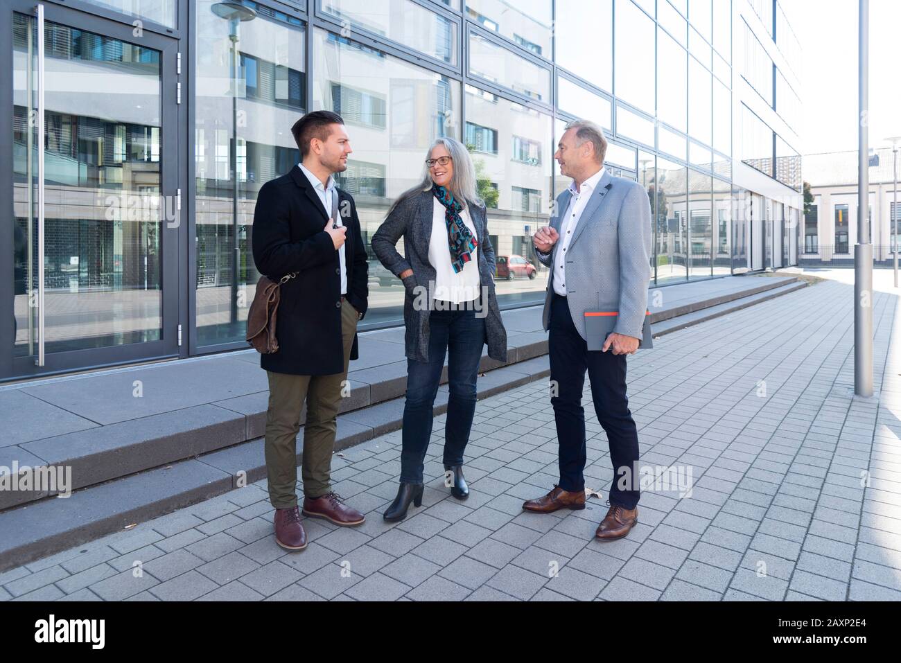 Three business people in front of modern office building Stock Photo ...