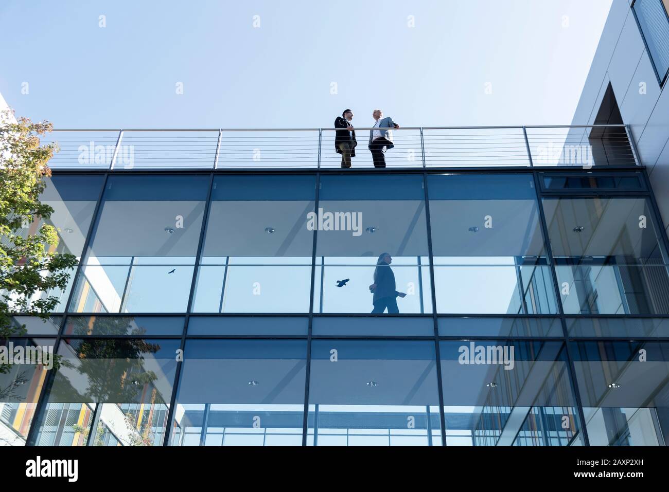 Two business people on balcony of modern office building Stock Photo ...
