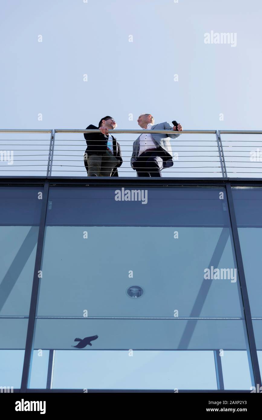 Two business people on balcony of modern office building Stock Photo ...