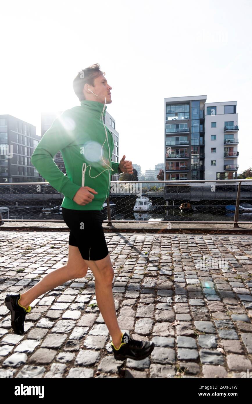 Sporty man jogging in the town, half portrait Stock Photo - Alamy