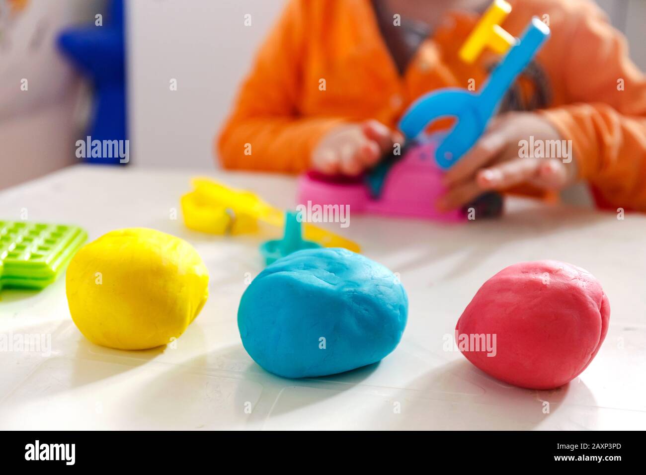 child playing a home made playdough. Yellow, orande and pink modelling ...