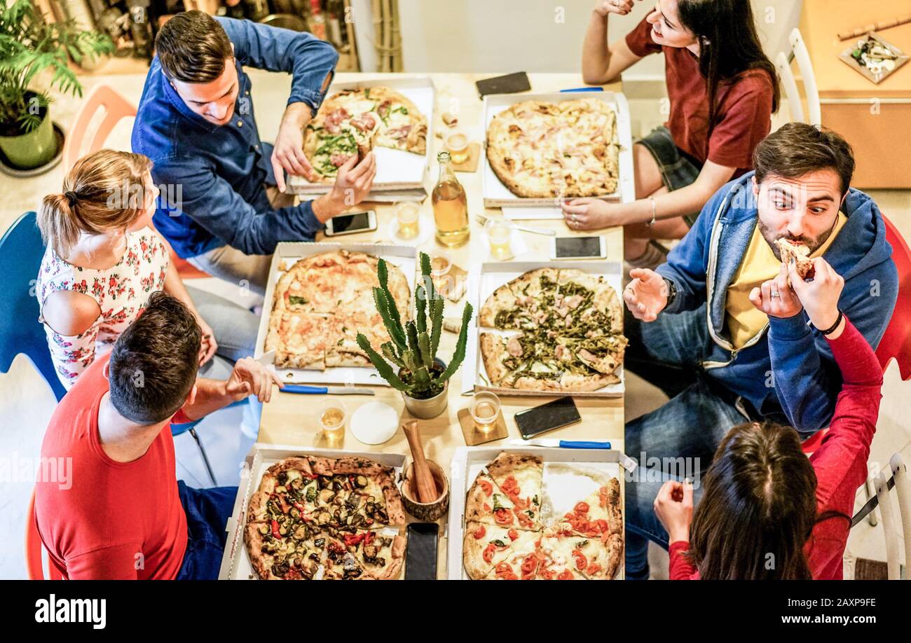 Top view of young friends eating italian pizza take away and toasting ...