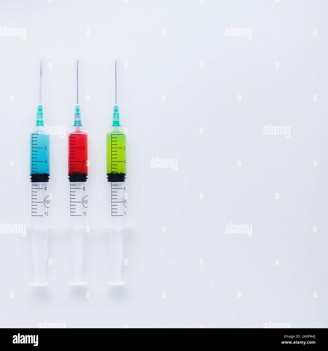 Three syringes filled with blue, red and green liquids on white ...