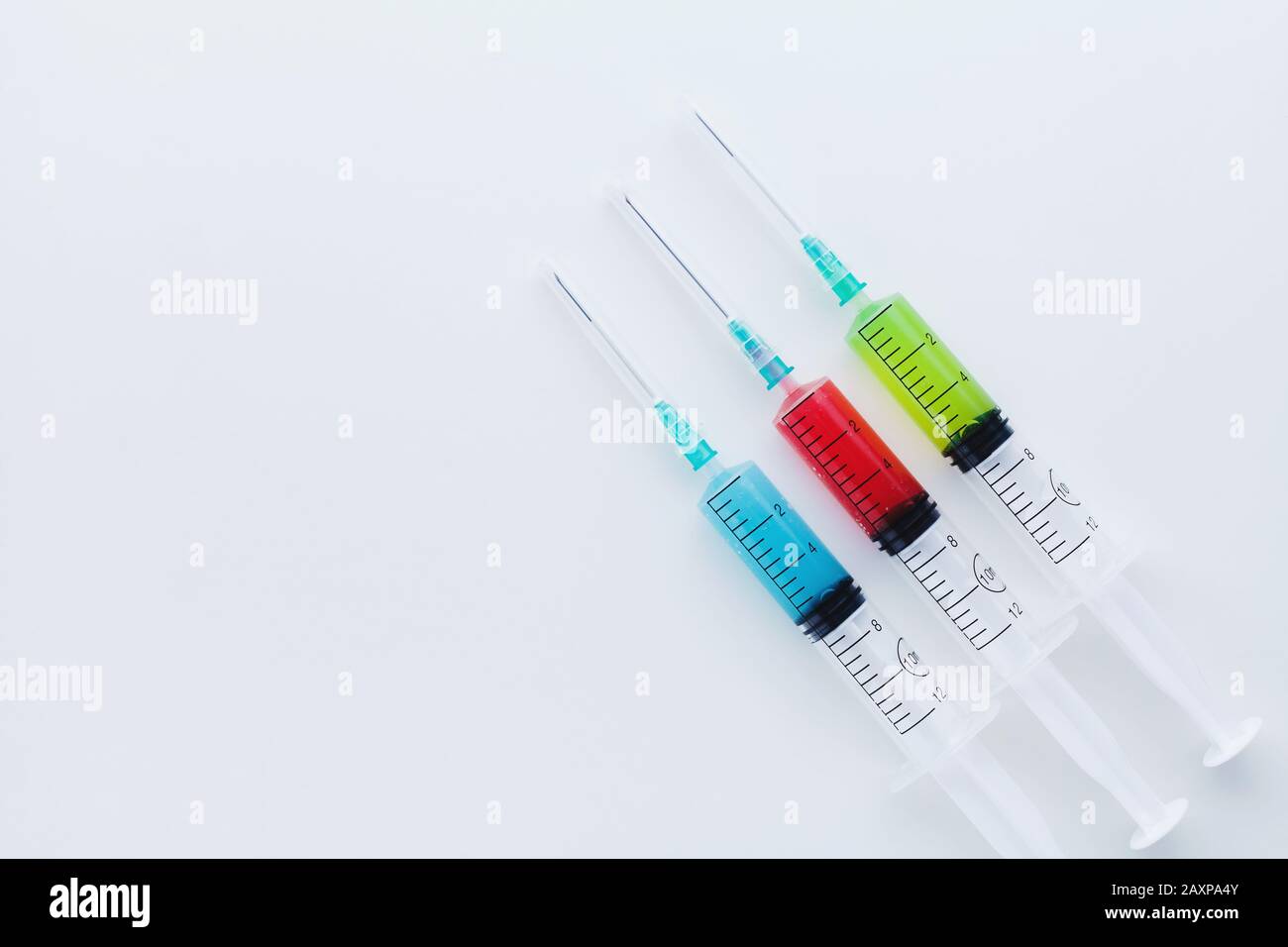 Three syringes filled with blue, red and green liquids on white ...