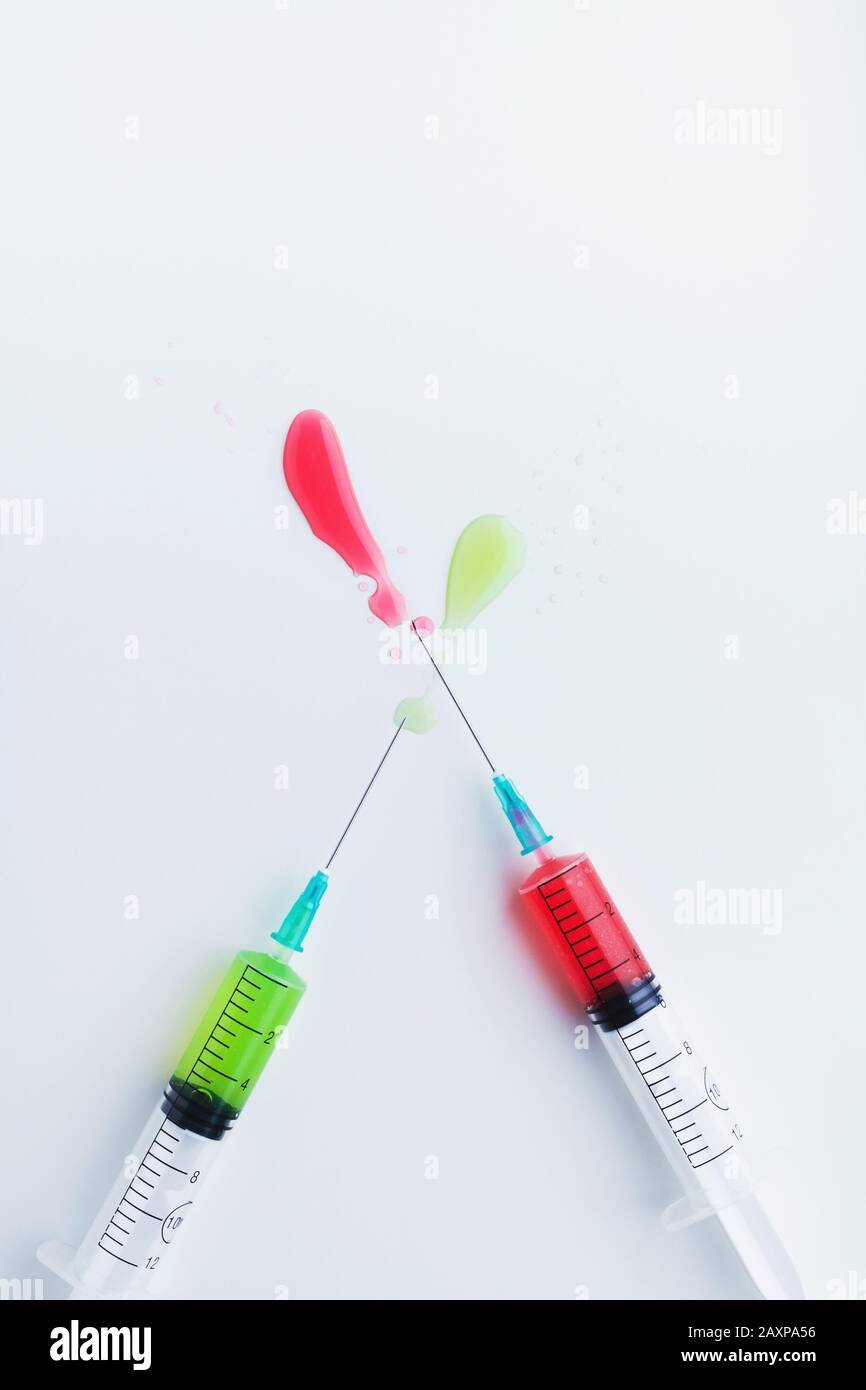 Two syringes filled with green and red liquids on white background ...