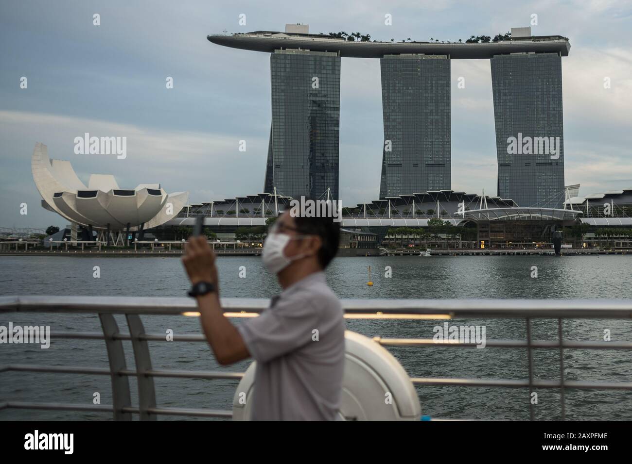 A man wearing protective surgical masks takes pictures at the Merlion ...